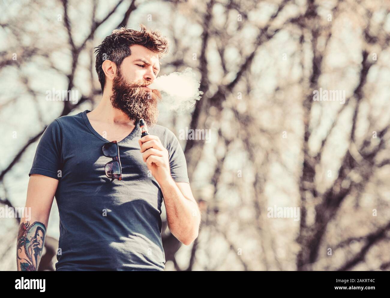 Bearded brutal male smoking electronic cigarette. hipster man hold ...