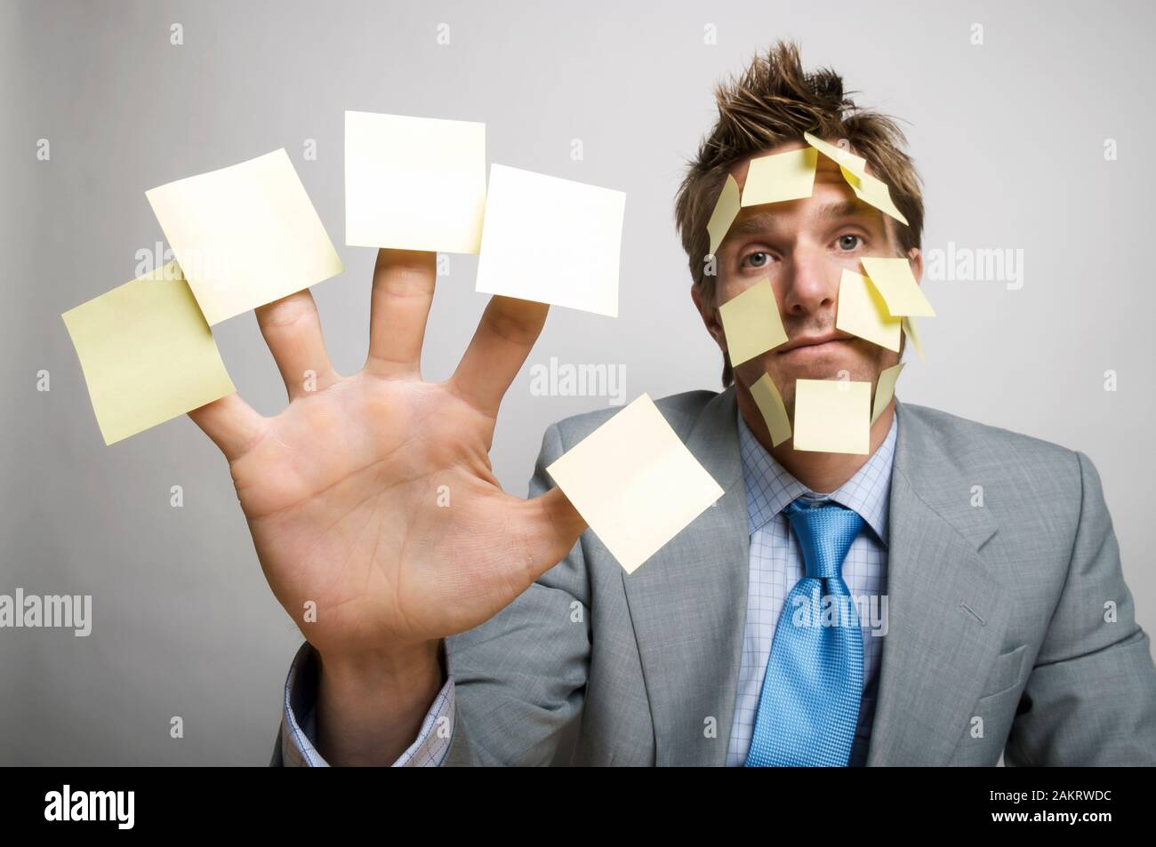 Overworked office worker sitting at his desk with yellow sticky notes ...