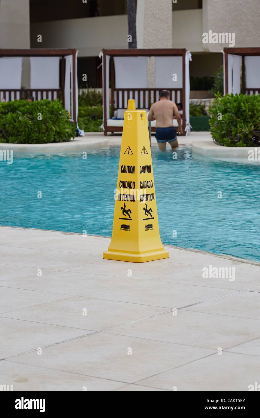 A caution sign on the edge of a swimming pool warning of a slippery ...