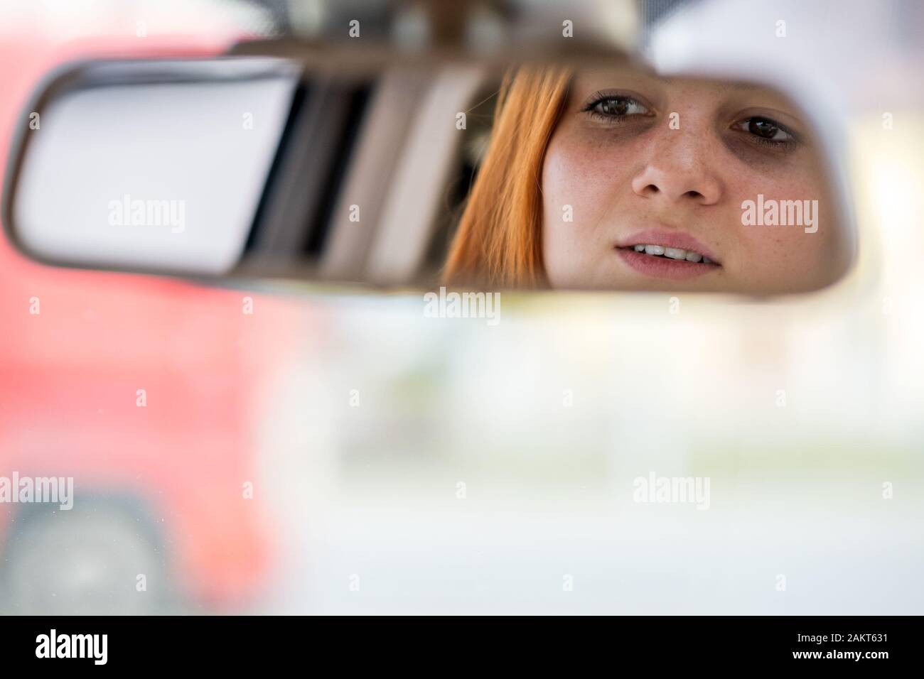 Young woman driver checking rear view mirror looking backwards while ...