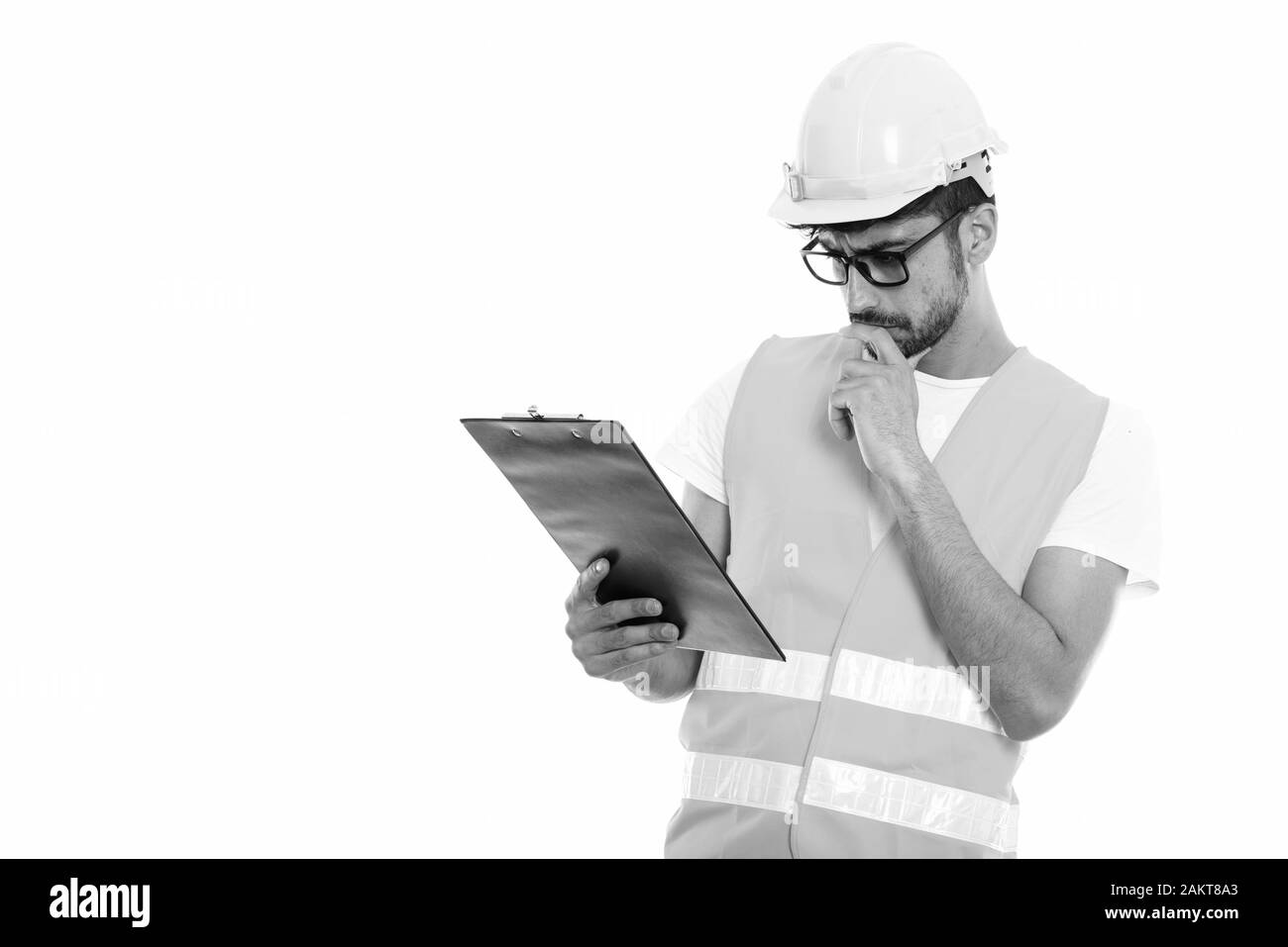 Studio shot of young Persian man construction worker thinking while ...