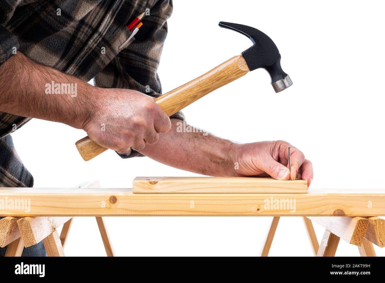 Close-up. Carpenter with hammer and nails fixes a wooden board ...