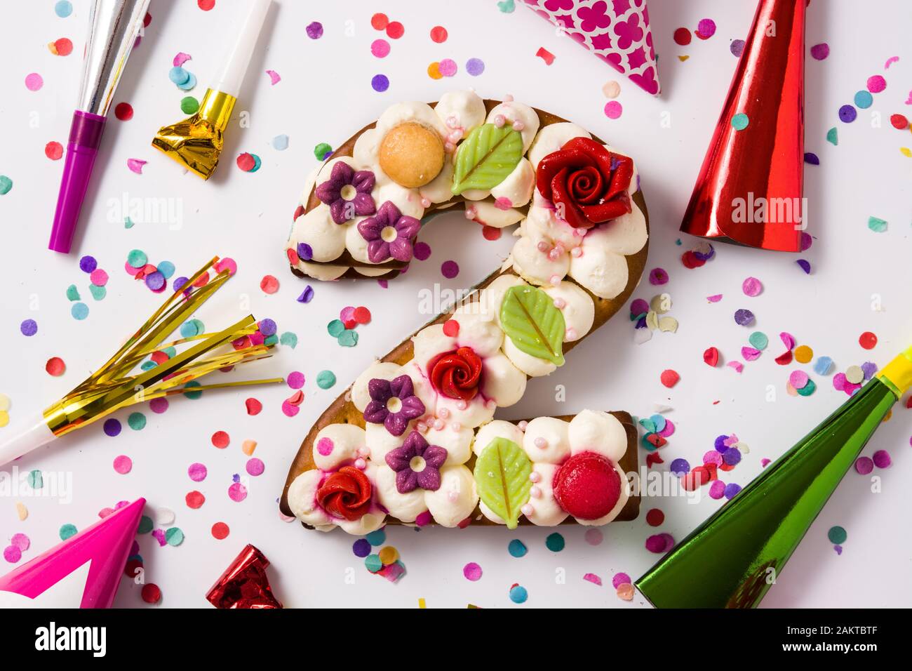 Number two cake decorated with flowers, macarons and confetti isolated ...