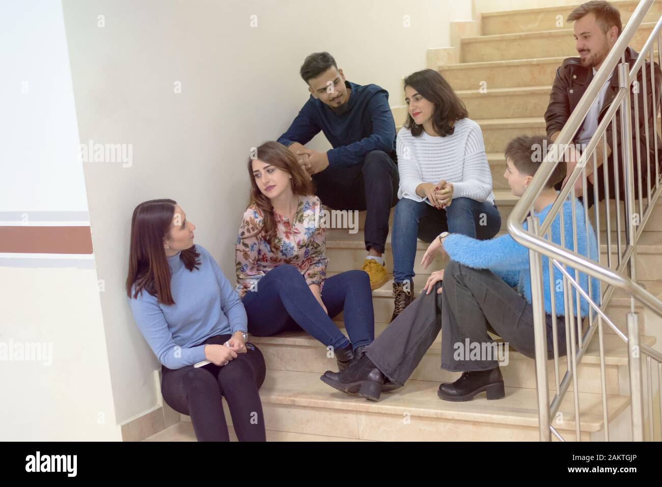Multiethnic group of students sitting on school stairs smiling ...