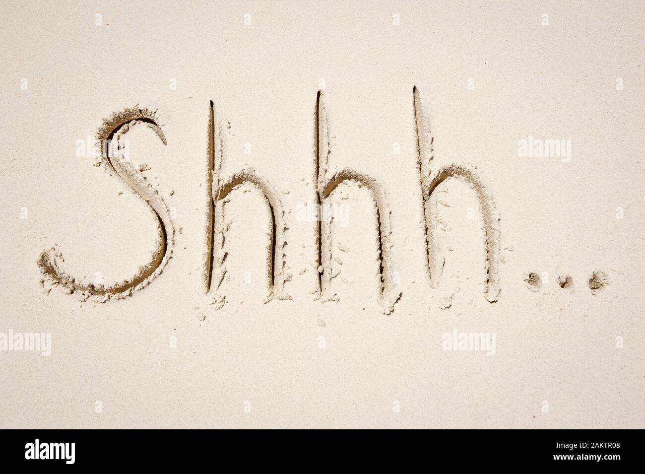 Shhh... message handwritten in textured script in smooth sand on a ...