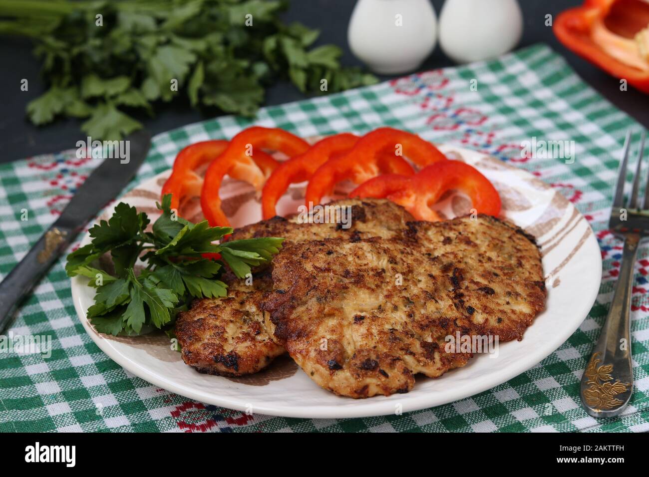 Turkey chops and sweet pepper on a plate against a dark background ...