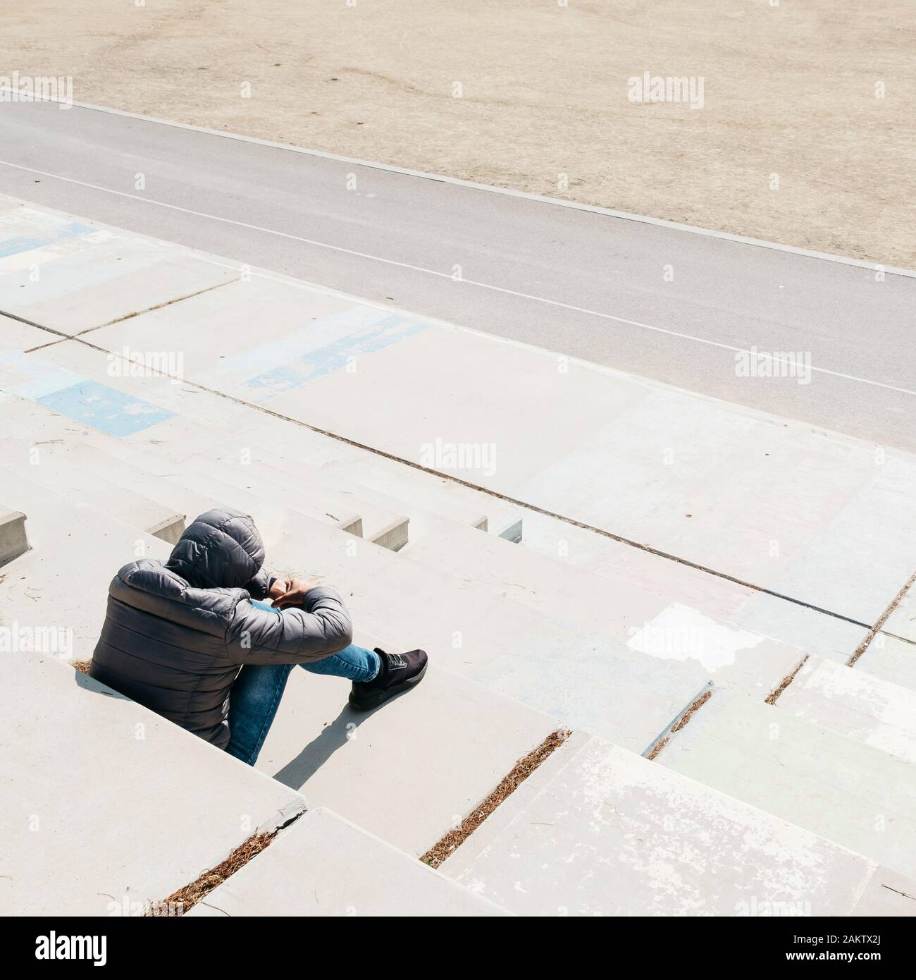 a young caucasian man, seen from behind, wearing jeans and a gray ...