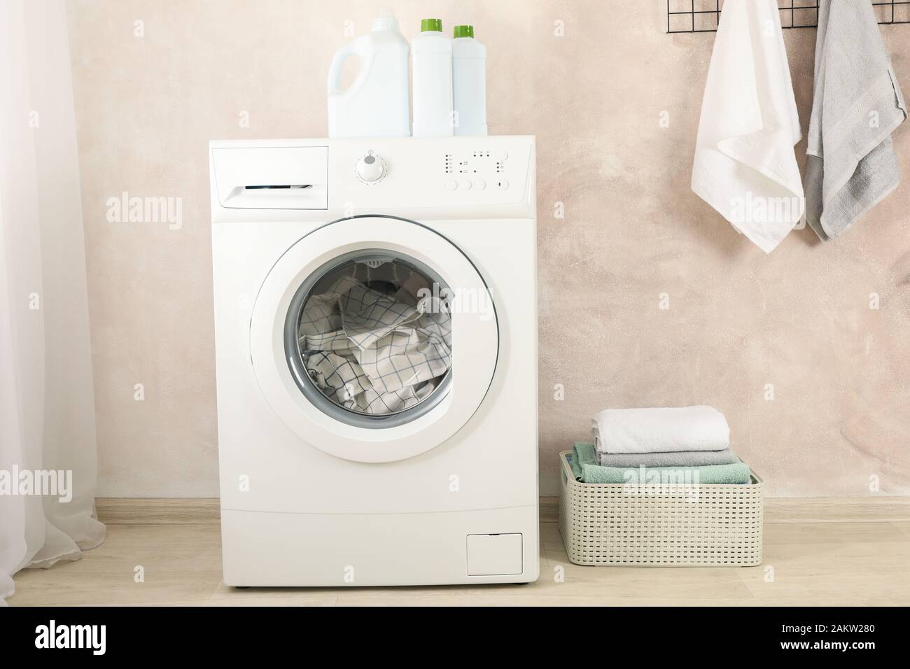 Laundry room with washing machine against light brown wall Stock Photo ...