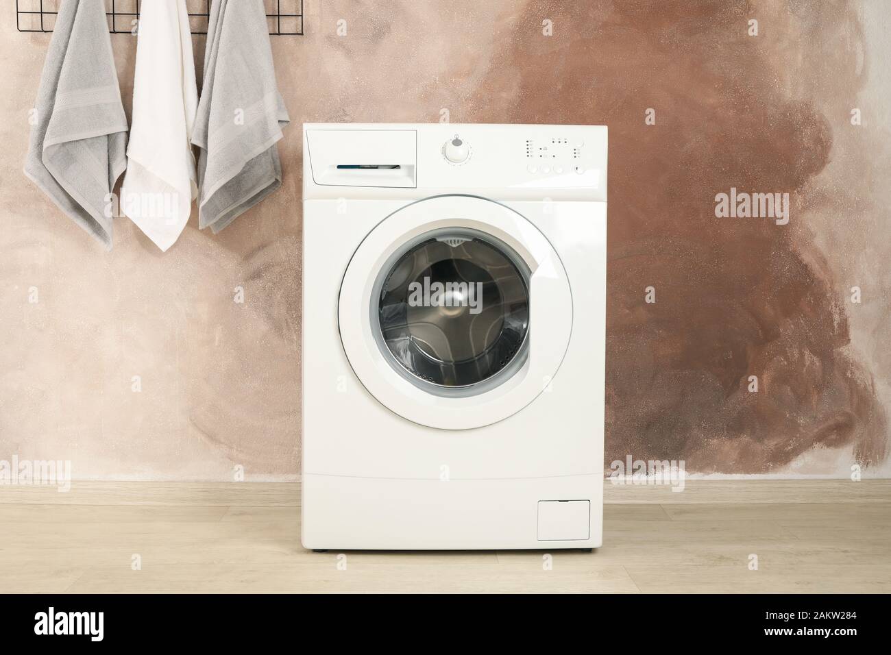 Laundry room with washing machine against brown wall Stock Photo - Alamy