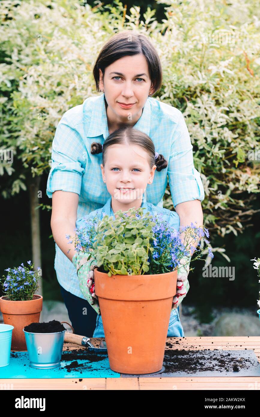 Mother and daughter planting flowers in pots in the garden - concept of ...