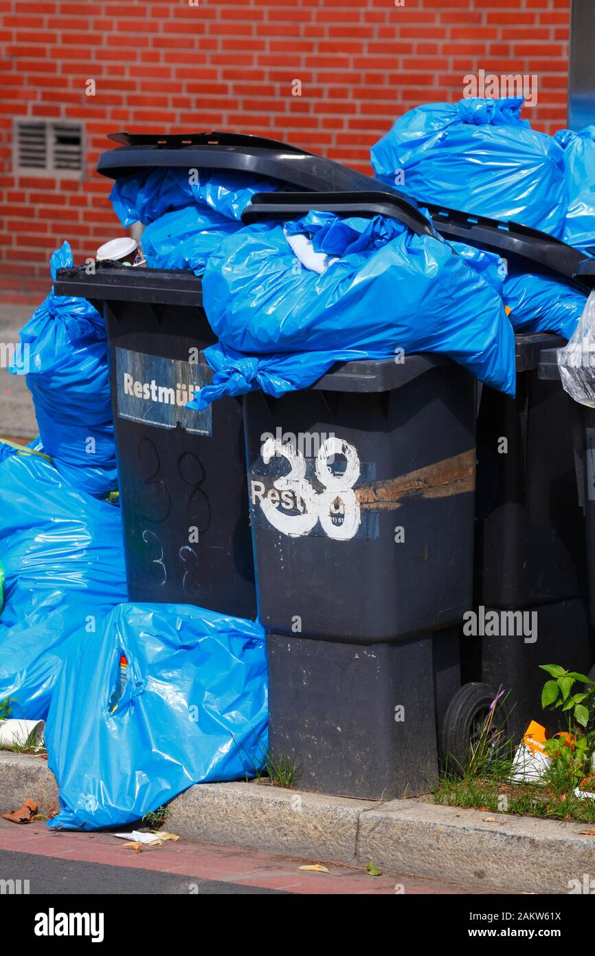 Blue garbage bags and black garbage bins for residual waste standing on ...