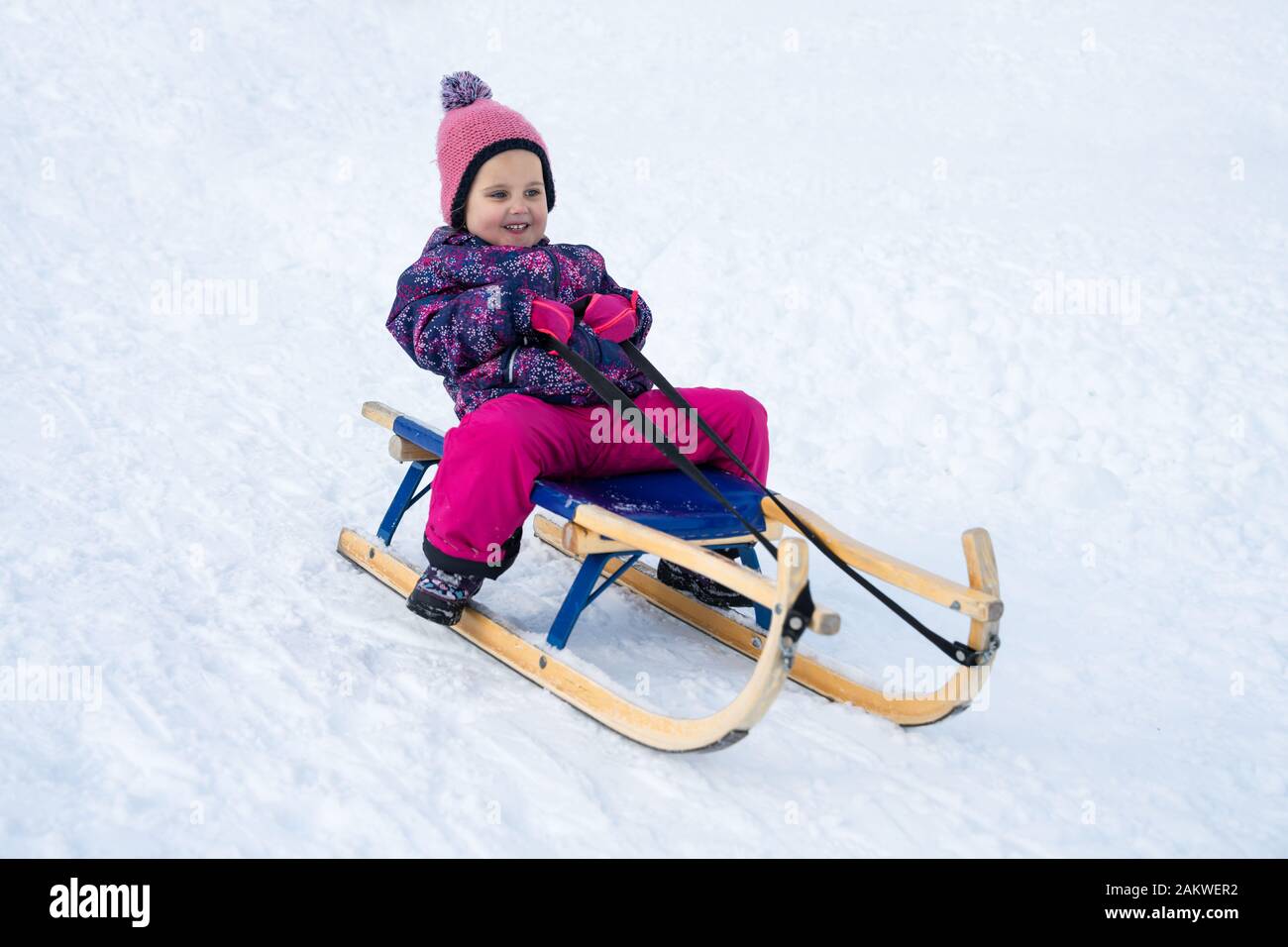 Cheerful Little Girl Sliding With Sledge In The Snow At Laax Stock ...
