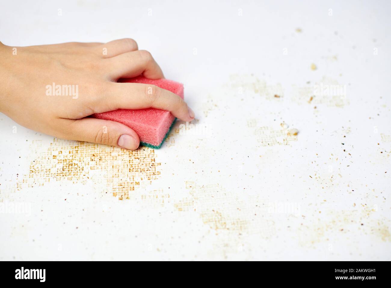 Cleaning kitchen table. Pink sponge in woman hand removes dirt, bread ...
