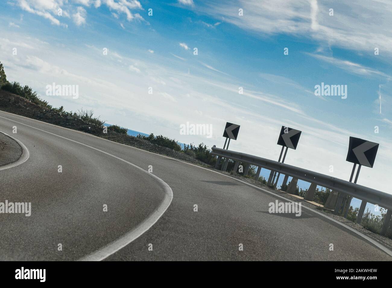 A sharp bend on an empty tarmac road with street signs. Edge of the ...