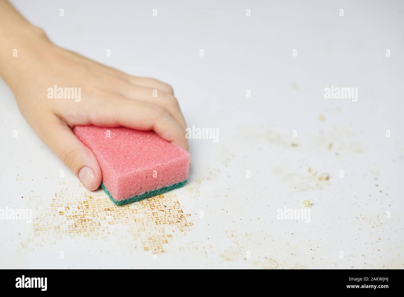 Cleaning kitchen table. Pink sponge in woman hand removes dirt, bread ...
