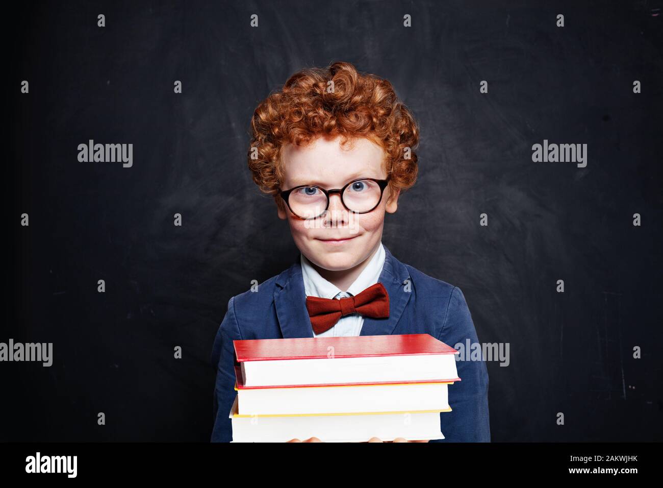 Clever child in primary school uniform and books on blackboard ...