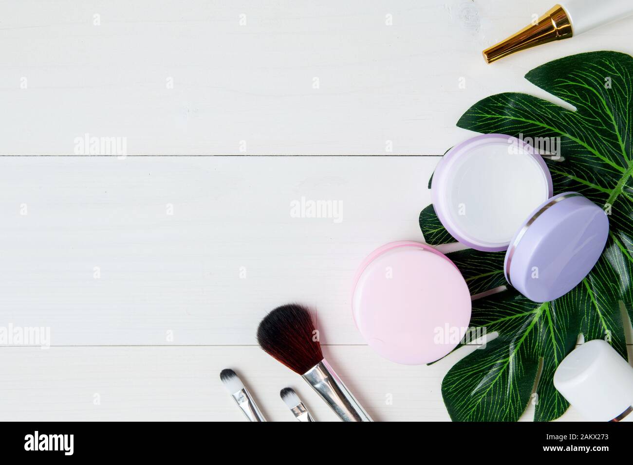 cosmetic and skin care product and green leaves on white wood table ...