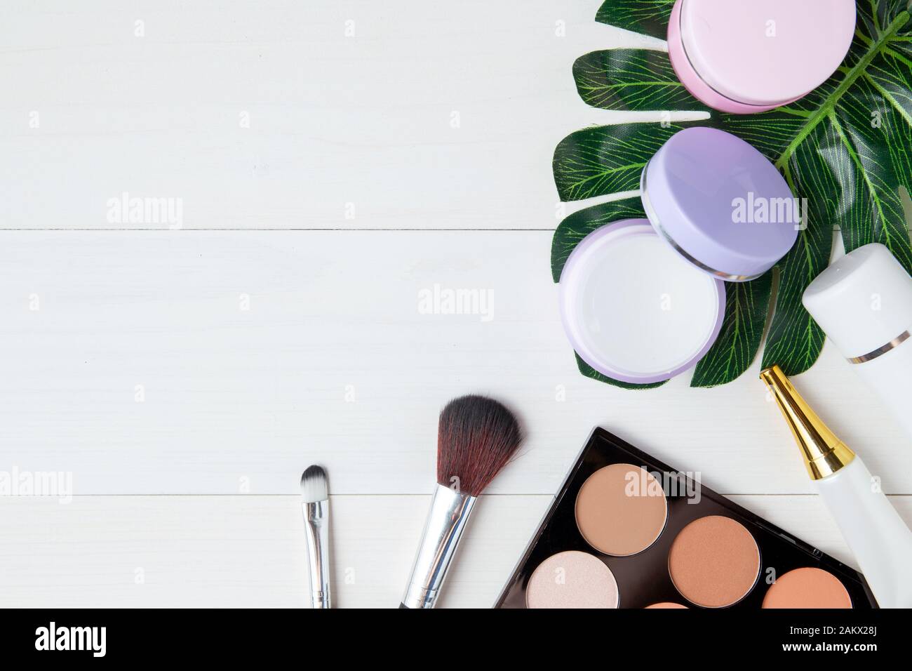 cosmetic makeup and skin care product and leaves on white wood table ...