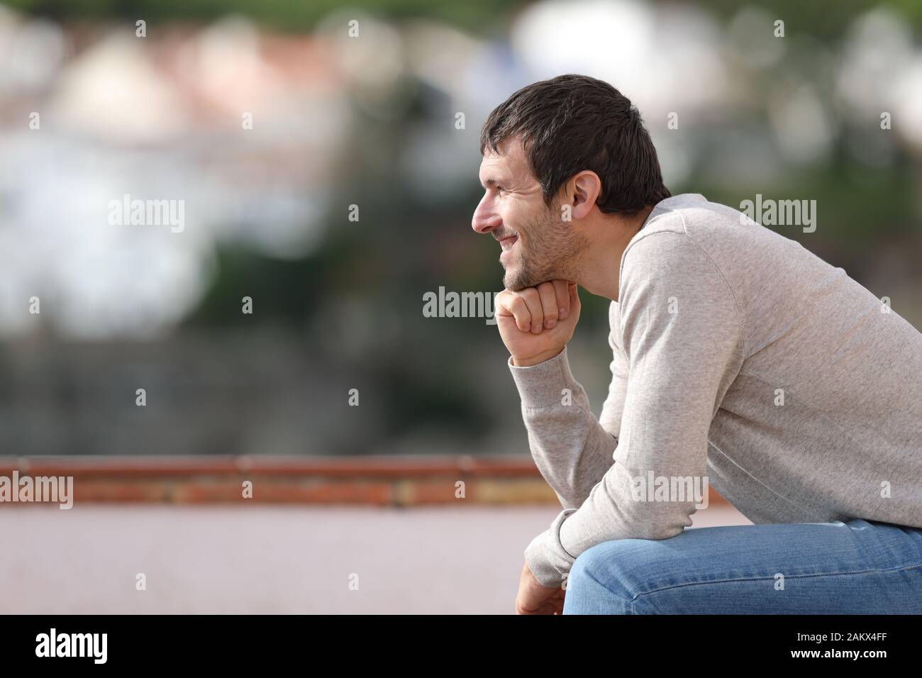 Side view portrait of a happy man contemplating views sitting on a ...
