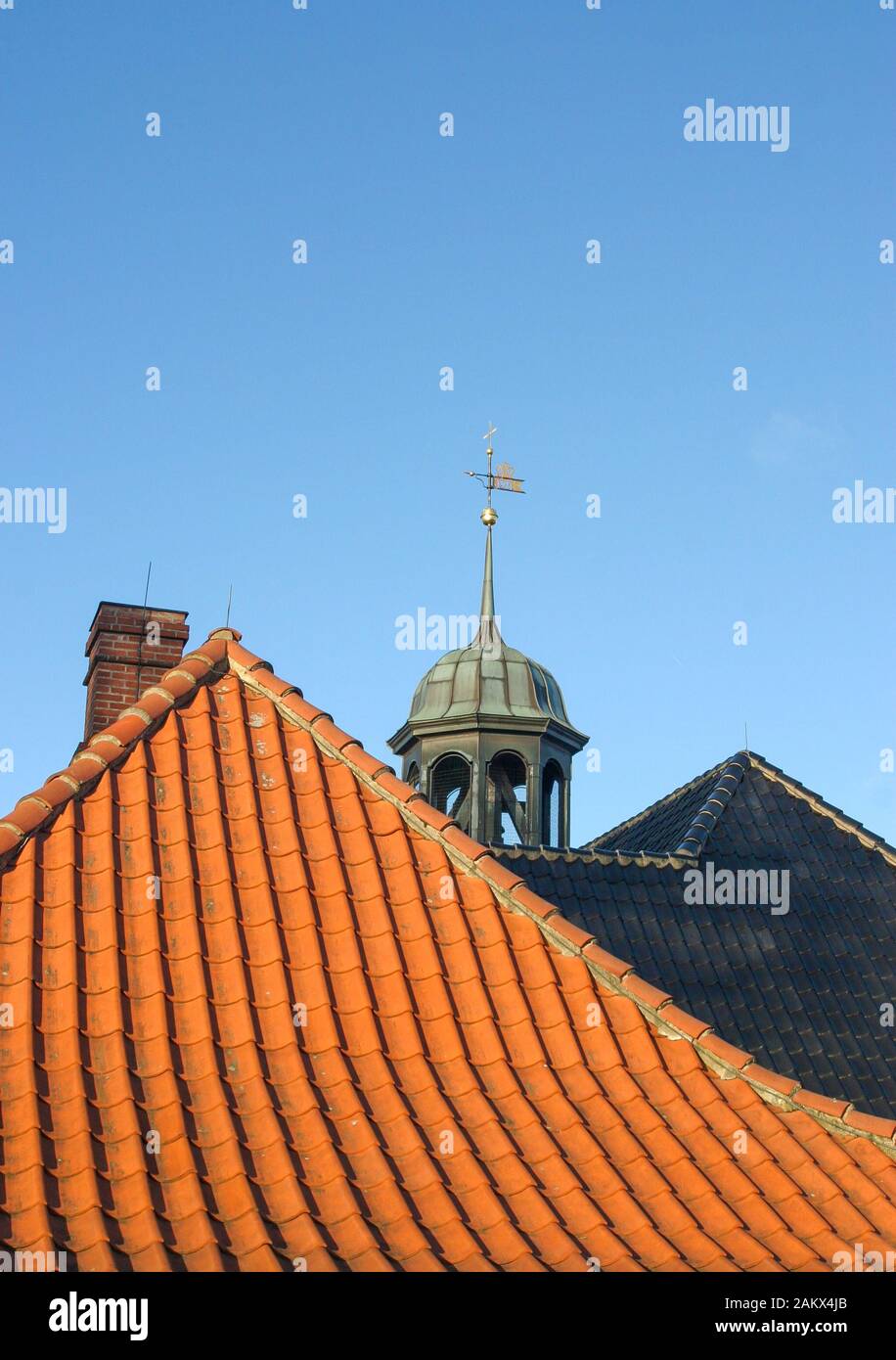 Gable roof with rows of orange terracotta roof tiles and a green church ...