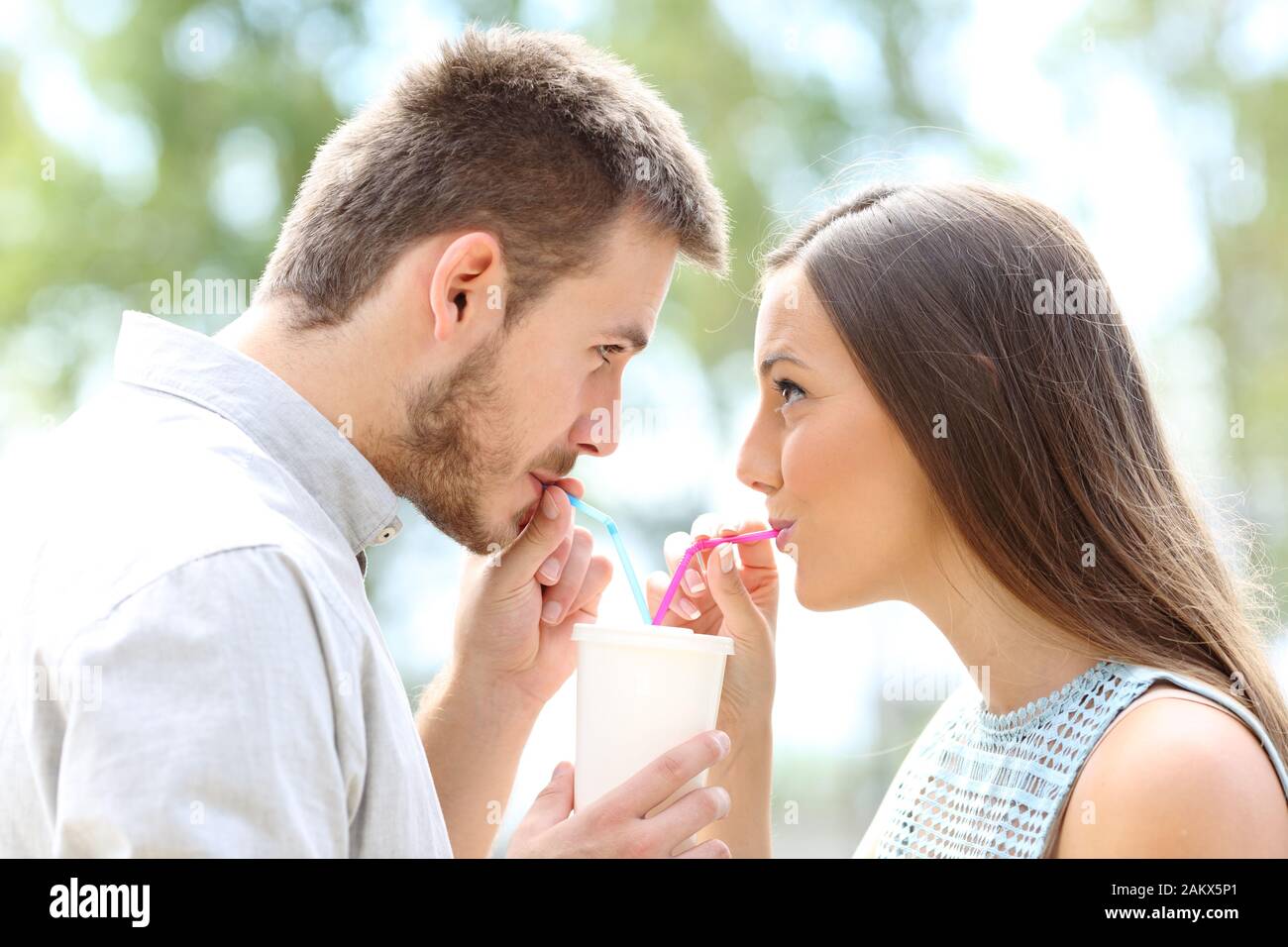 Side view portrait of a couple sipping a takeaway drink together using ...