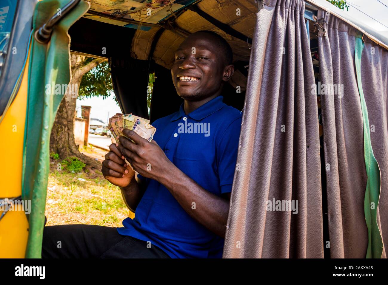 young african man driving a rickshaw taxi counting his money smiling ...