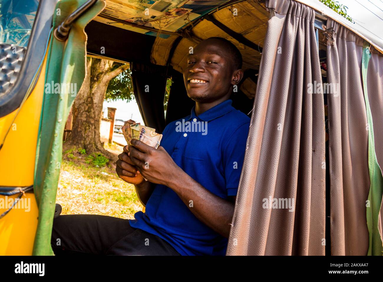 young african man driving a rickshaw taxi counting his money smiling ...