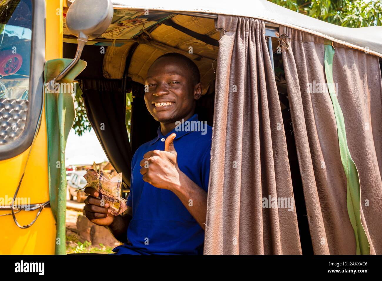 young african man driving a rickshaw taxi counting his money smiling ...