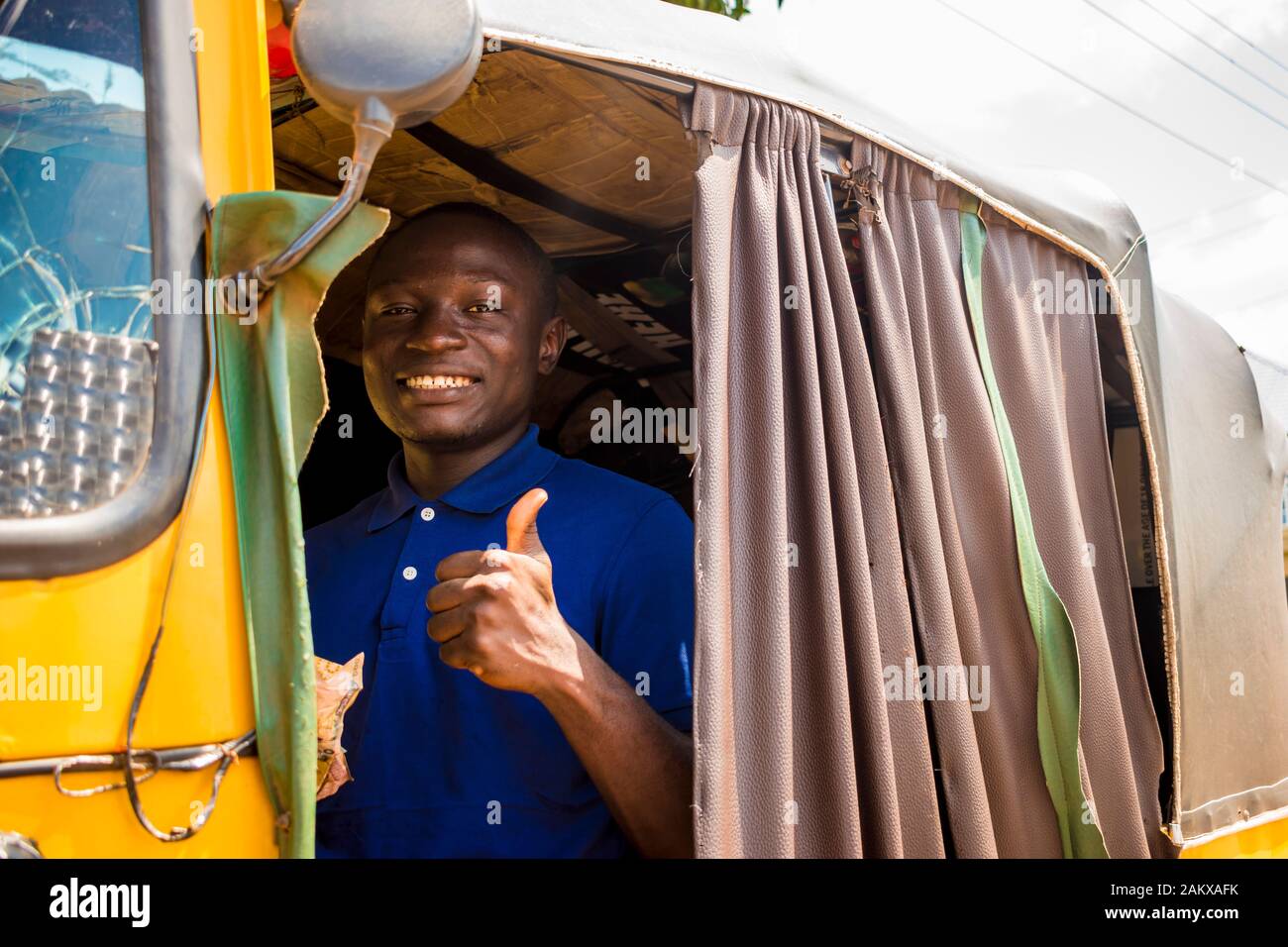 young african man driving a rickshaw taxi counting his money smiling ...