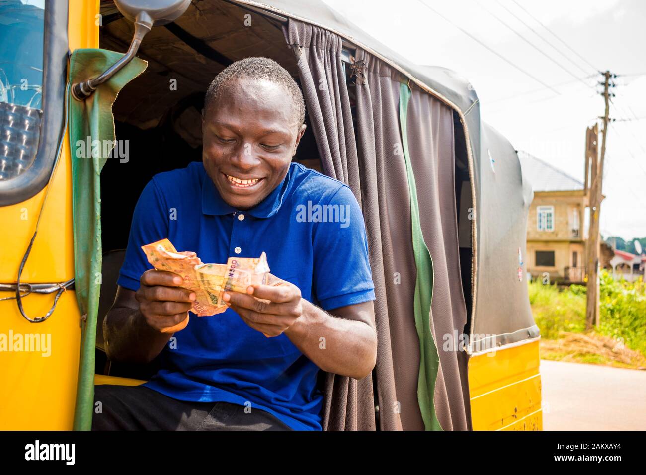 young african man driving a rickshaw taxi counting his money smiling ...