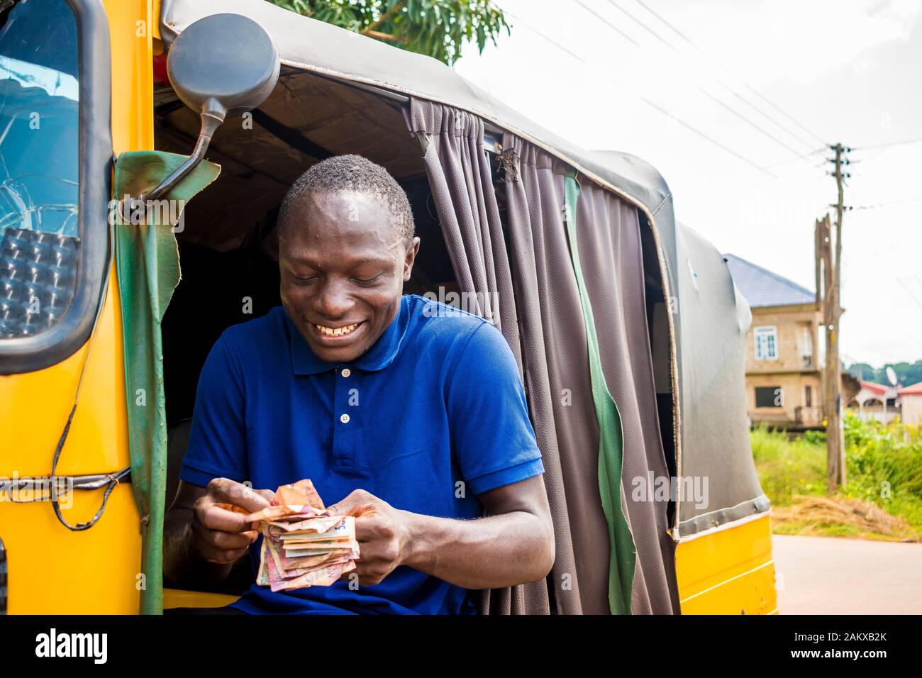 young african man driving a rickshaw taxi counting his money smiling ...