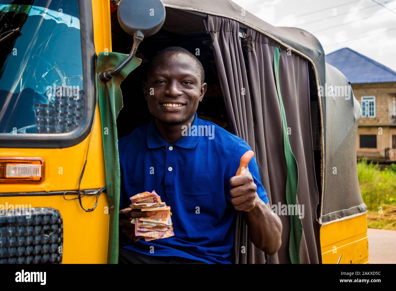 young african man driving a rickshaw taxi counting his money smiling ...