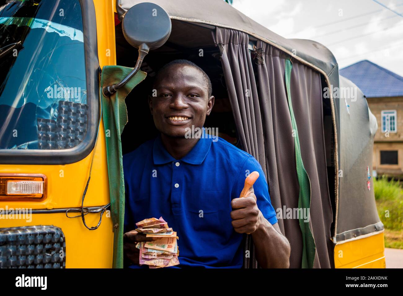 young african man driving a rickshaw taxi counting his money smiling ...