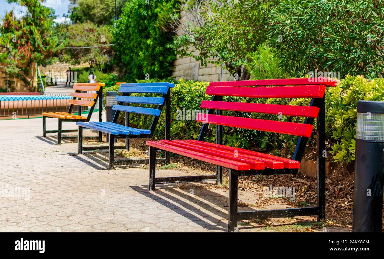 Three benches, red, blue and yellow, in the park Stock Photo - Alamy