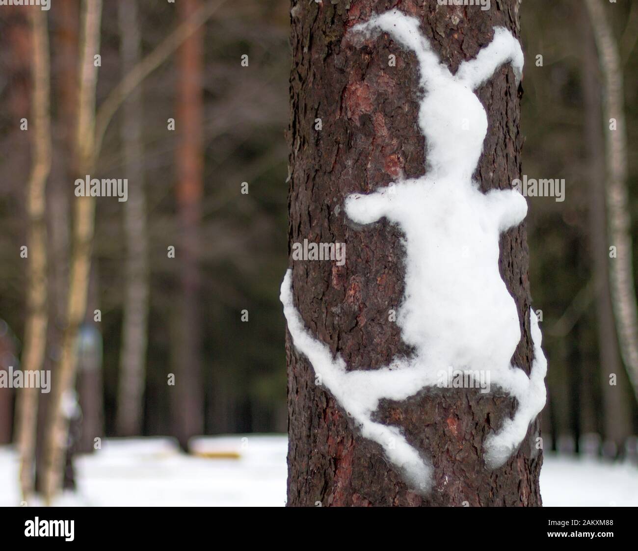 a back view of a rabbit skiing made of snow on a tree trunk in a park ...