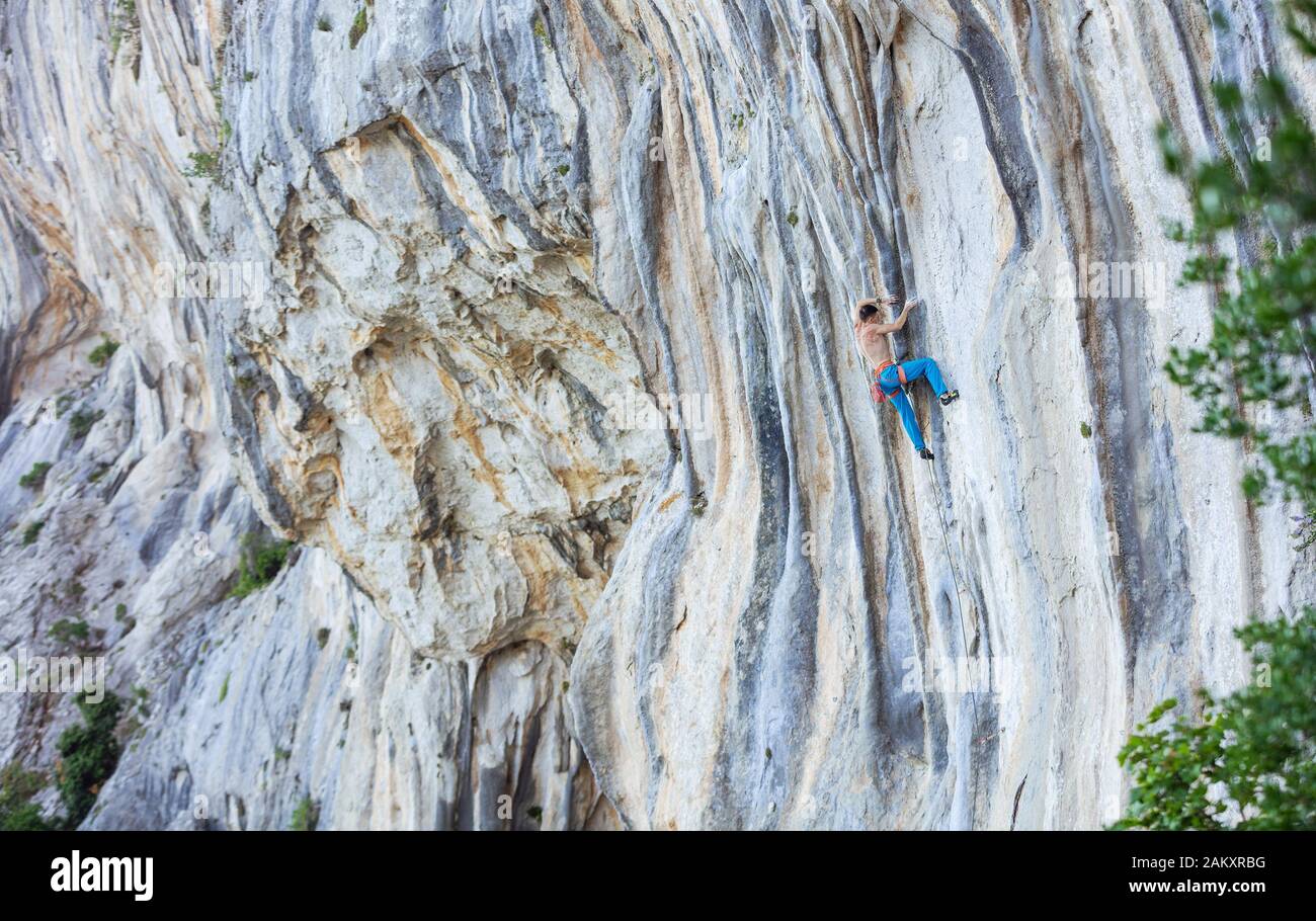 Caucasian young man climbing challenging route on overhanging cliff ...