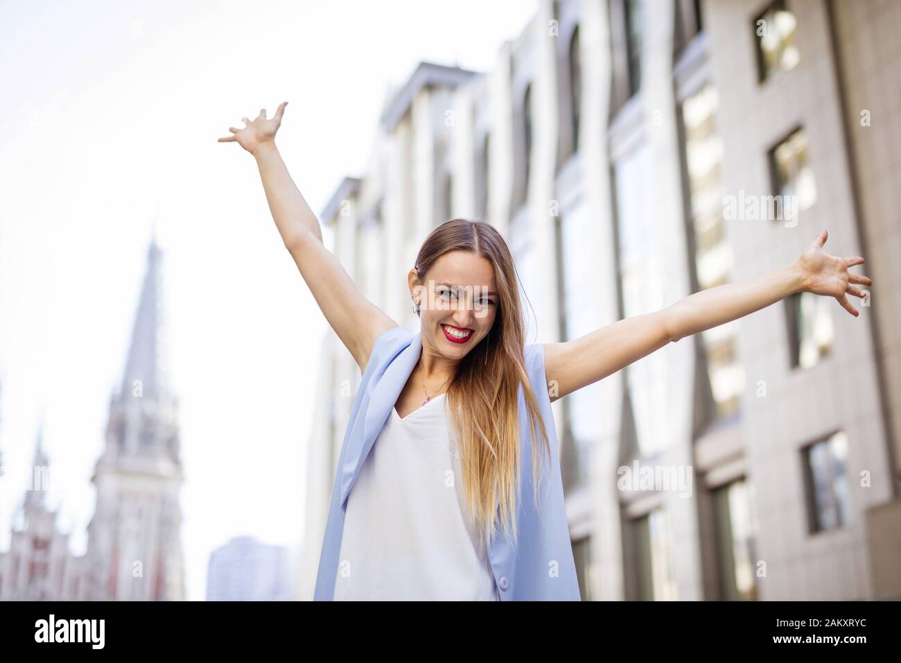 Happy young woman lifting her arms in joy downtown Stock Photo - Alamy