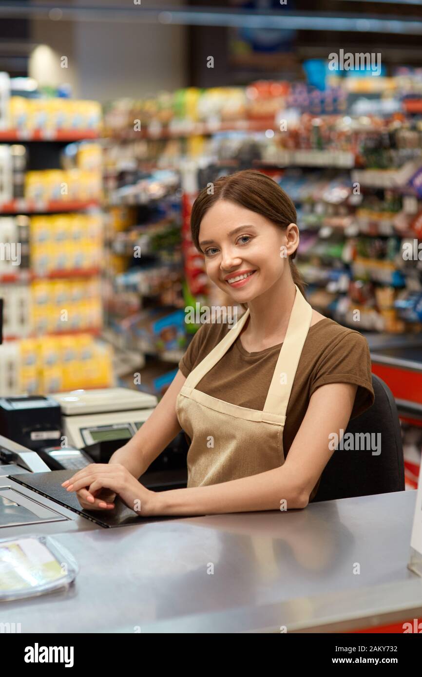 Daily Shopping. Young cashier woman at the supermarket posing to camera ...