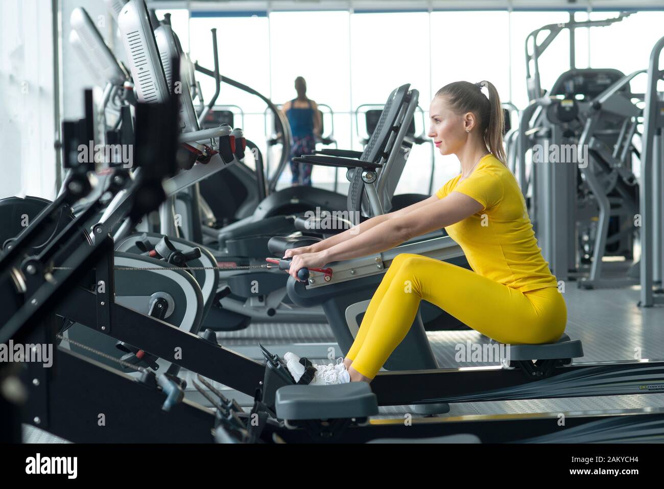 Side view of fit young women using rowing machine in health club Stock ...
