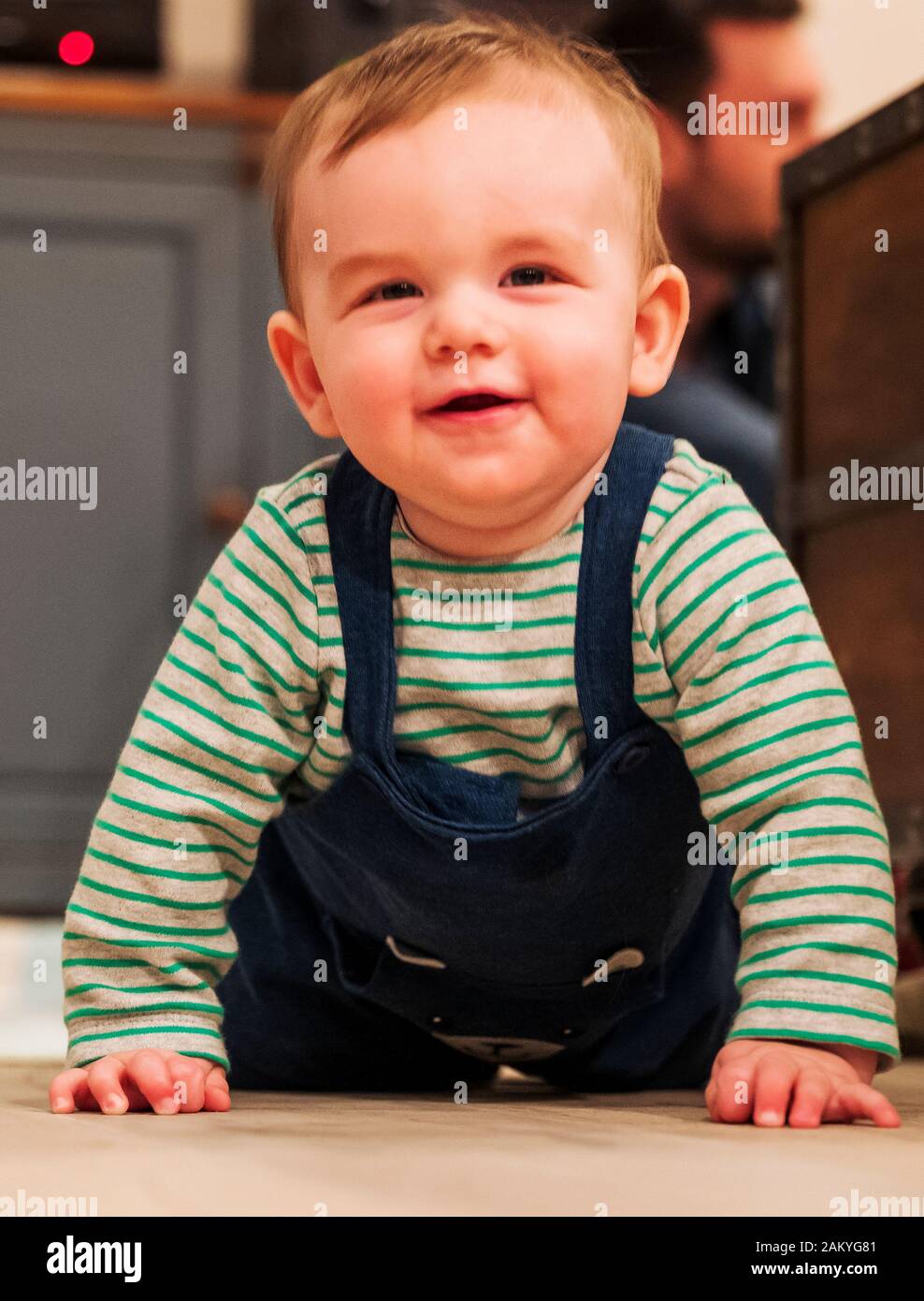 Seven month old baby boy happily crawling across living room floor ...