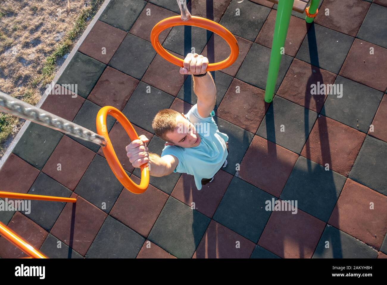 Young fit athlete working out at outdoor gym making dipping pull ups ...