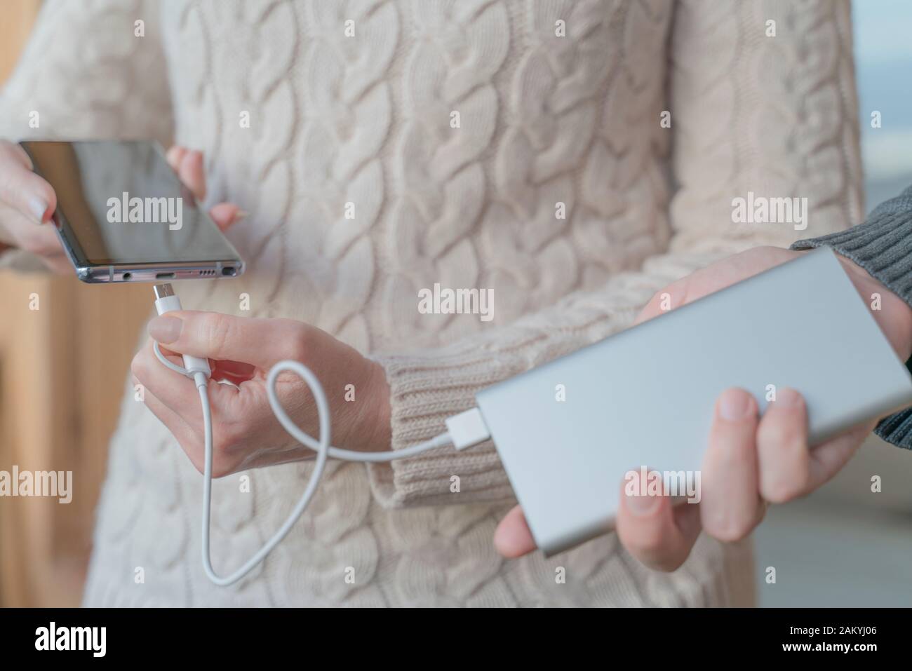 Two people, man and woman, sharing technology device charge. Silver ...