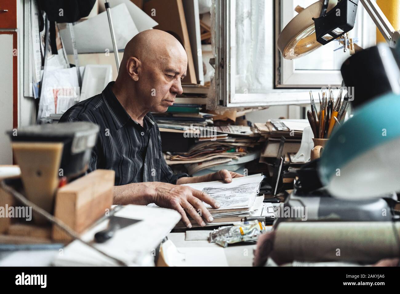 Artist working at art studio indoors looking at sketches pensive Stock ...