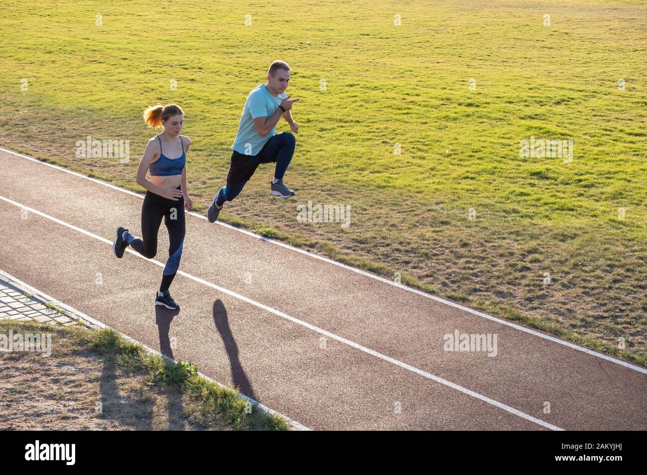 Young couple of fit sportsmen boy and girl running while doing exercise ...