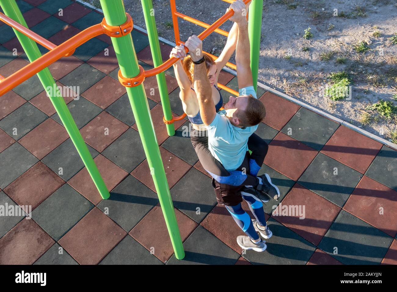 Young fit athlete working out at outdoor gym making dipping pull ups ...