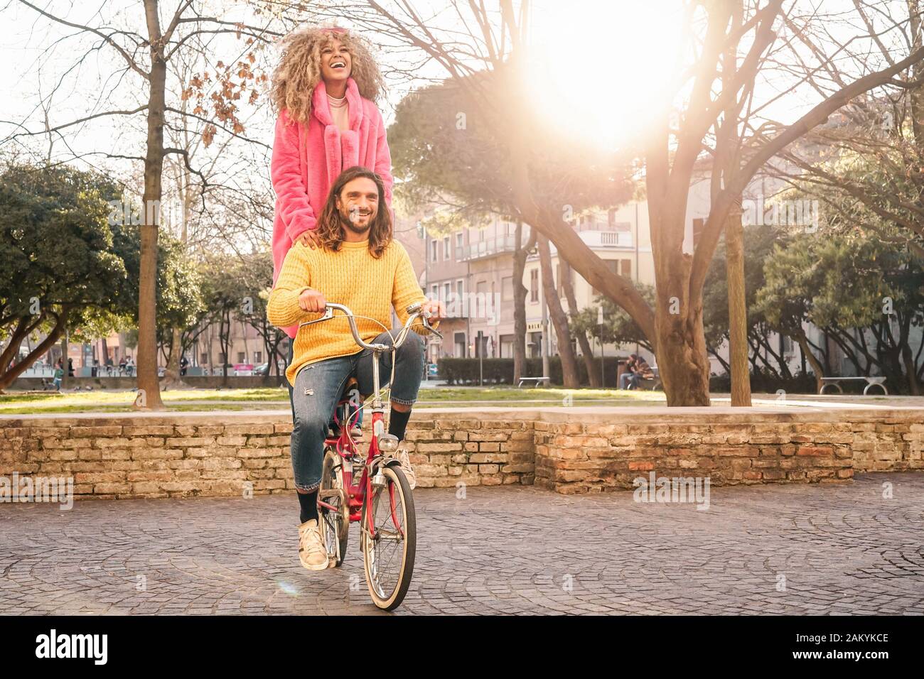 Happy couple riding on bicycle in the city center - Young people having ...