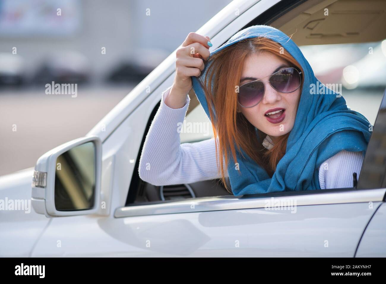Young fashionable smiling woman driver looking out the window behind ...