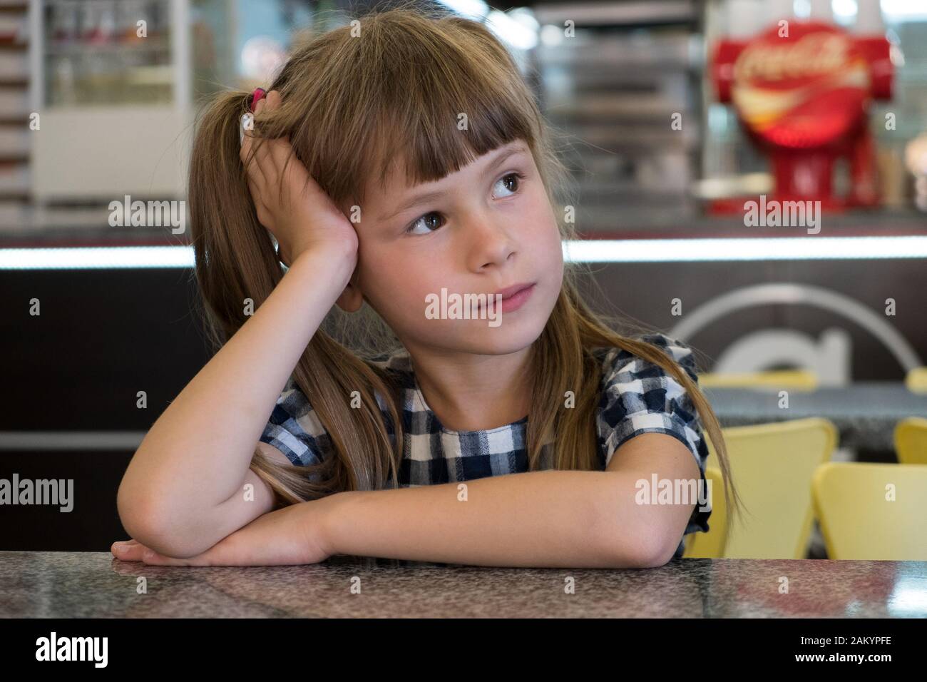 Child girl sitting in fast food restaurant behind empty table waiting ...