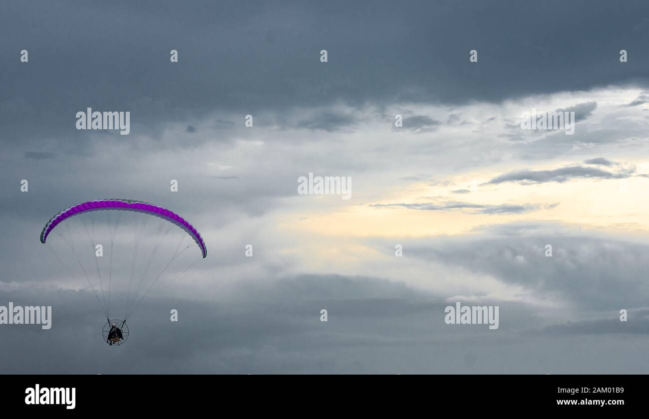 Paraglider flying during a dark cloudy sunset Stock Photo - Alamy