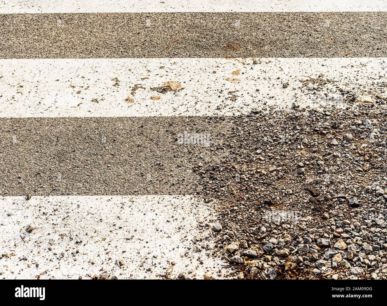Rocks and sand over the pedestrian zebra making a danger place to take ...